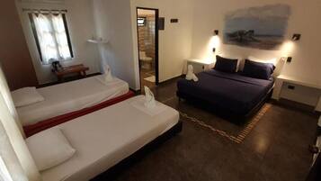 Quarto de hotel com duas camas de solteiro, uma cama grande, um quadro na parede e vista do quarto.