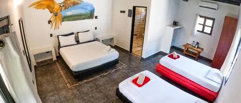 Quarto com cama, sofá, quadro de um pássaro e ventilador de teto.