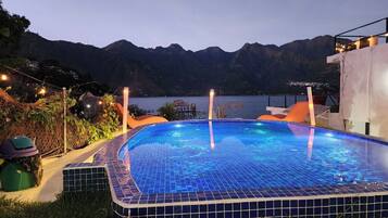 Piscina com vista para montanhas e um corpo de água.