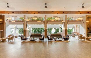 Um hall amplo com mobiliário moderno, janelas grandes e teto alto.