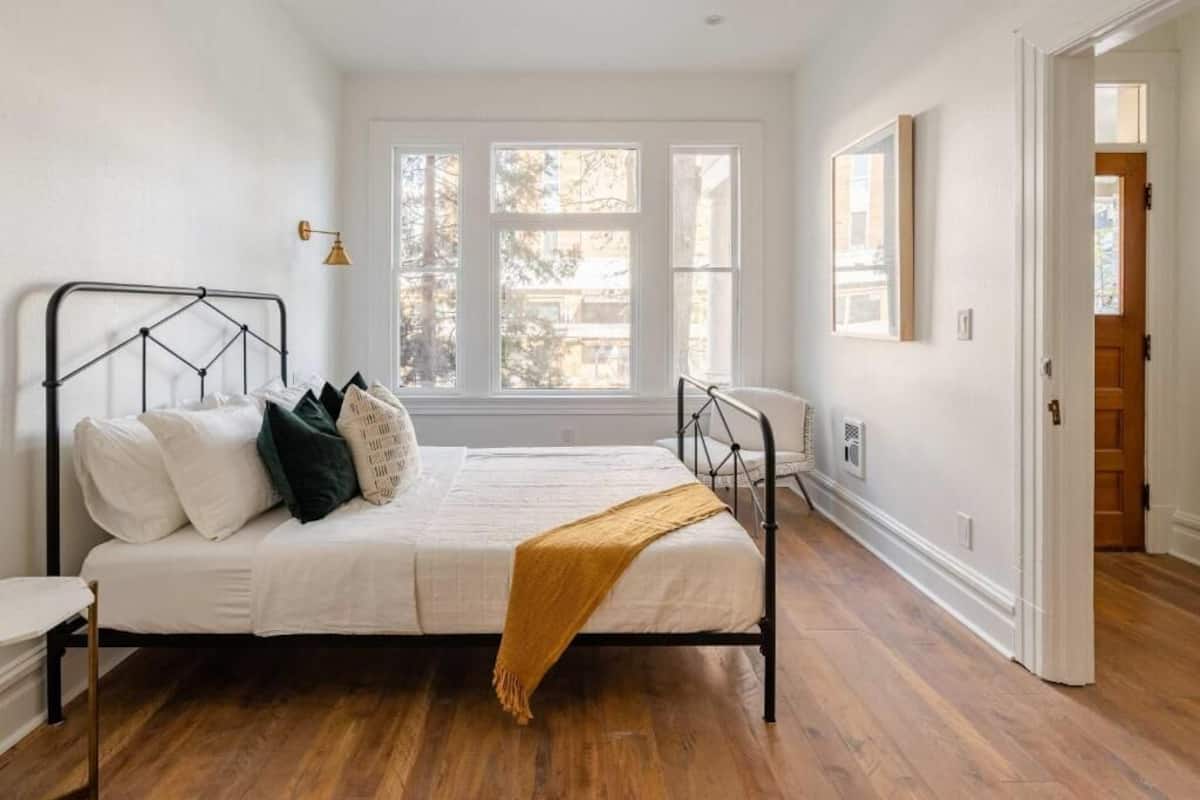 Quarto com cama, mesa de cabeceira, janela e radiador.