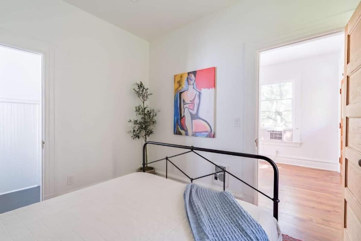 Quarto com cama, um quadro na parede e uma planta.