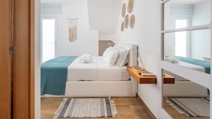 Quarto moderno com cama, mesa de cabeceira e espelho.