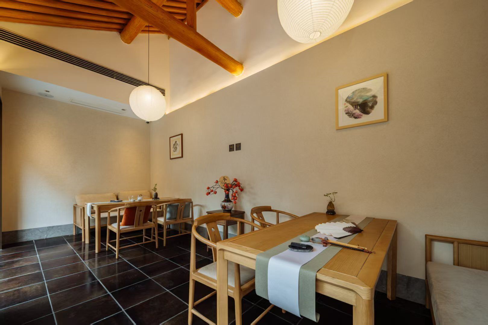 Uma área de refeições com uma mesa e cadeiras de madeira, um vaso com flores e um lustre.