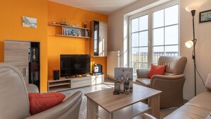 Uma sala de estar moderna com televisão, máquina de café e estante.