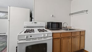 Uma cozinha compacta com fogão branco, micro-ondas e armários de madeira.