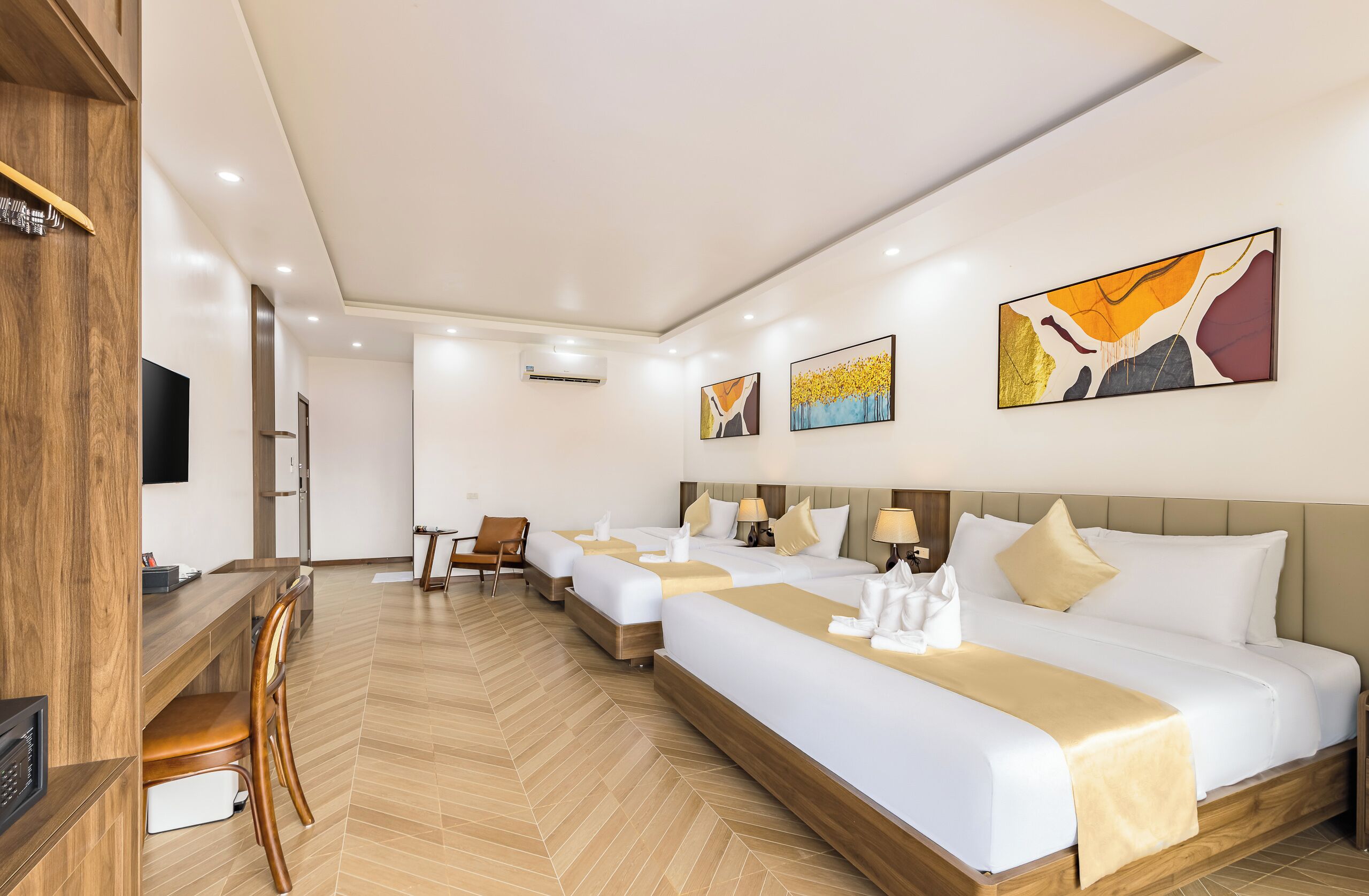 Quarto de hotel com uma cama grande, uma escrivaninha, uma cadeira e obras de arte nas paredes.