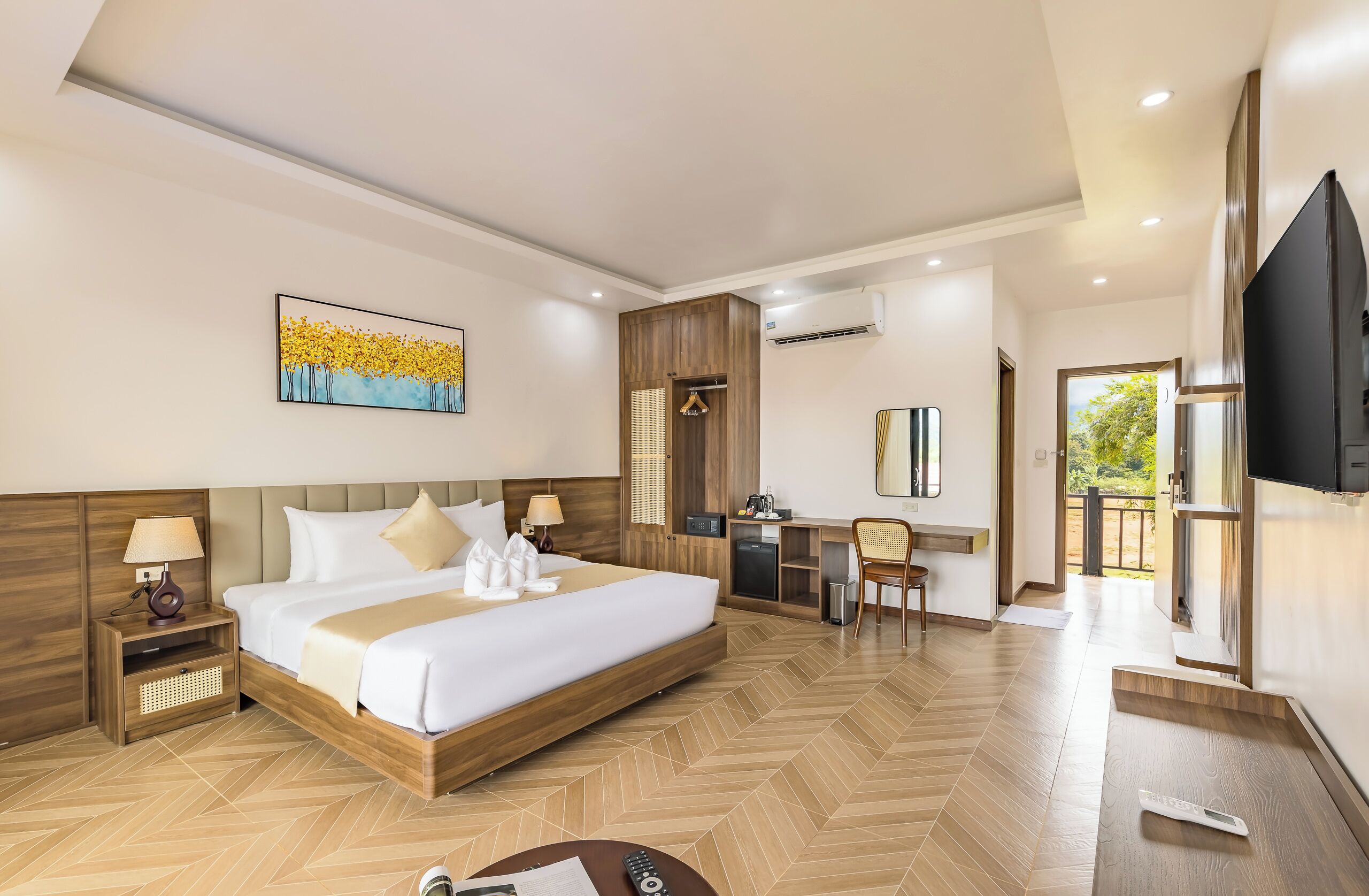 Quarto de hotel com cama grande, uma mesa de trabalho, televisão e varanda.