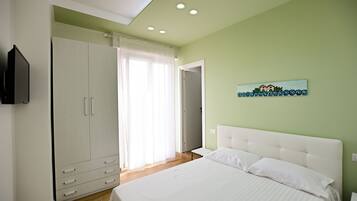 Quarto com cama, guarda-roupa, um quadro e televisão.