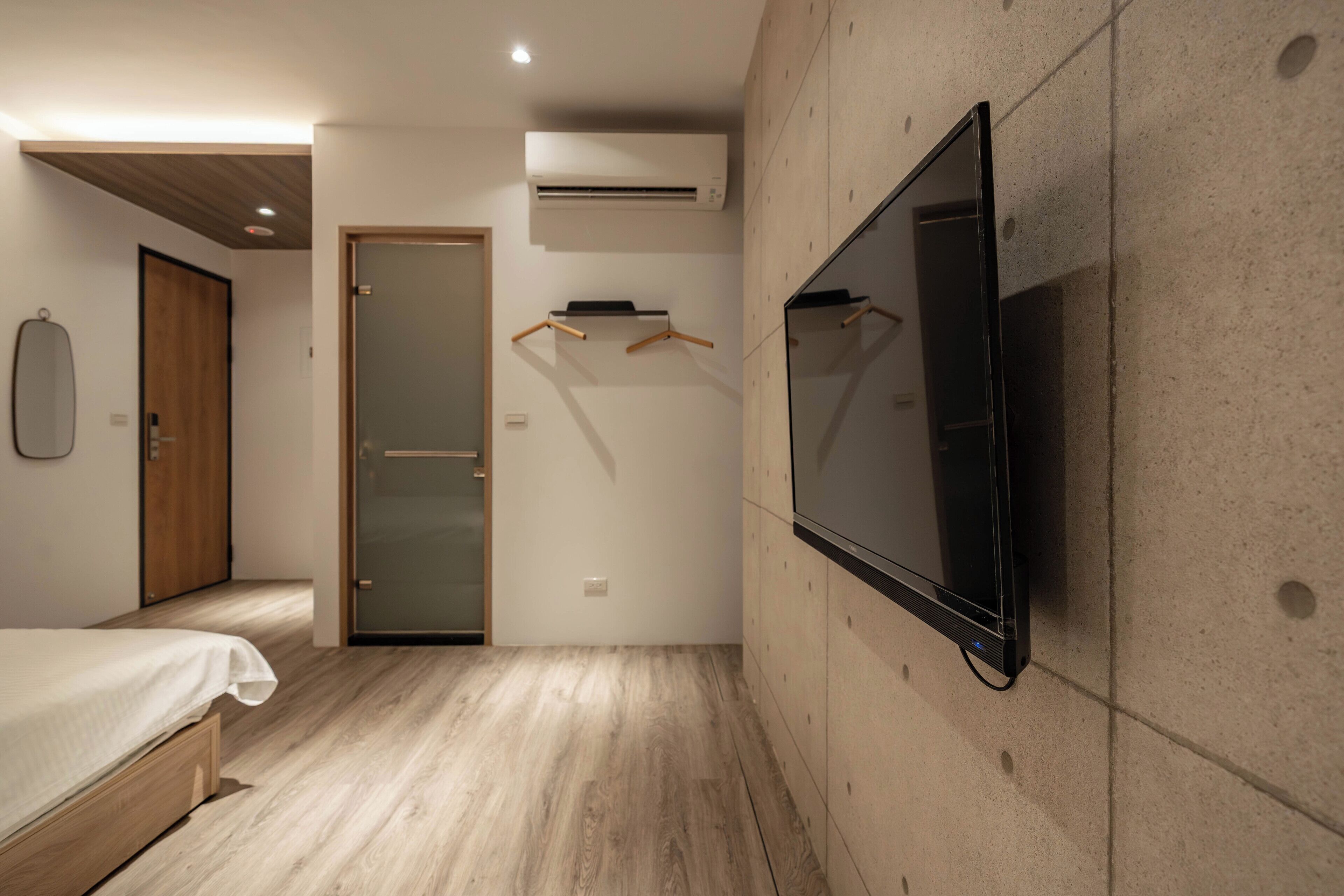 Quarto moderno com cama, televisão na parede e guarda-roupa.