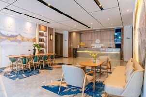 Um saguão de hotel moderno com balcão de recepção, área de estar e espaço para refeições.
