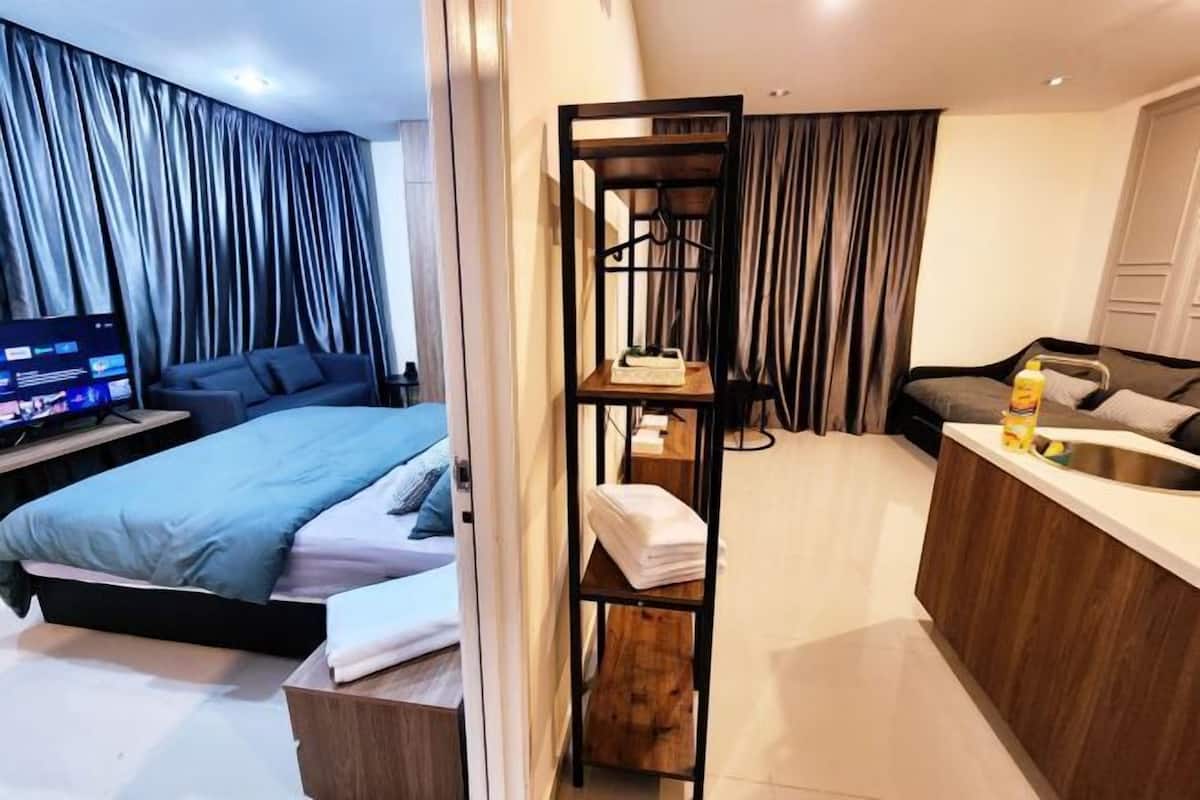 Quarto de hotel moderno com cama, escrivaninha, televisão e banheiro.