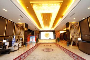 Um hall de hotel com uma recepção, um lustre grande e um tapete estampado.