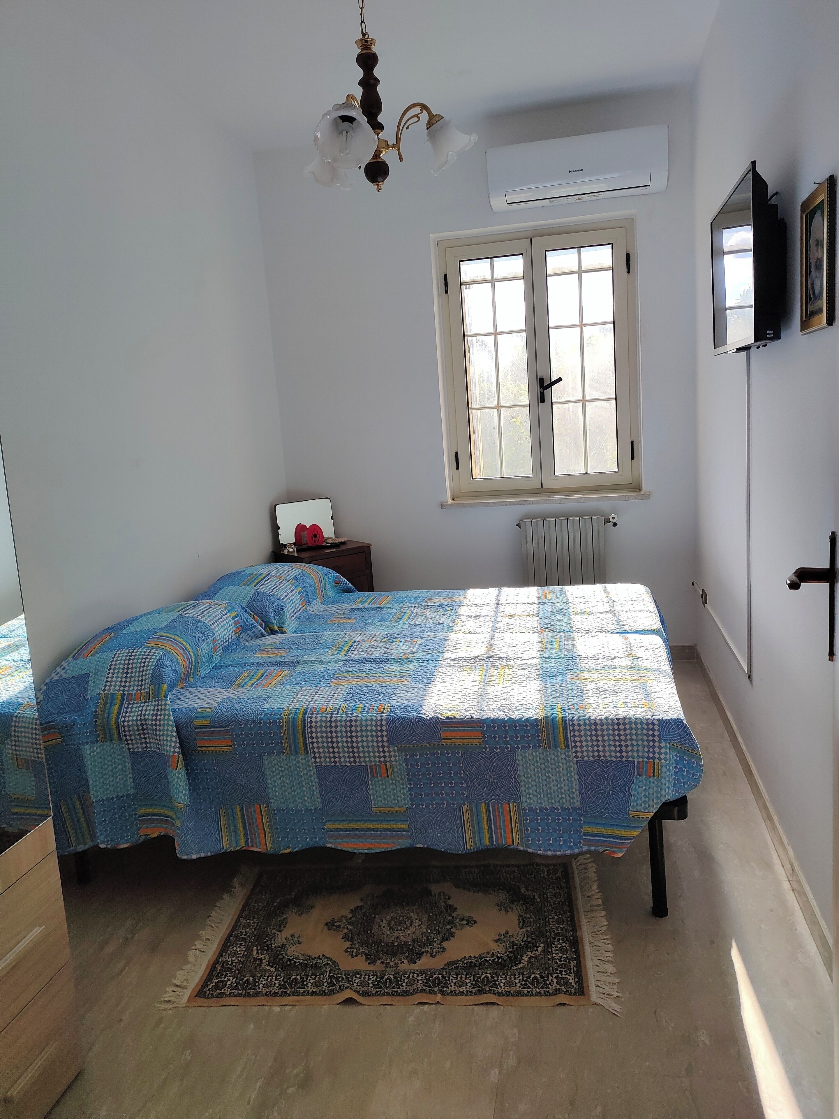 Quarto com cama, janela, ar condicionado e radiador.