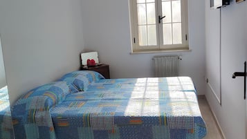 Quarto com cama, janela, ar condicionado e radiador.