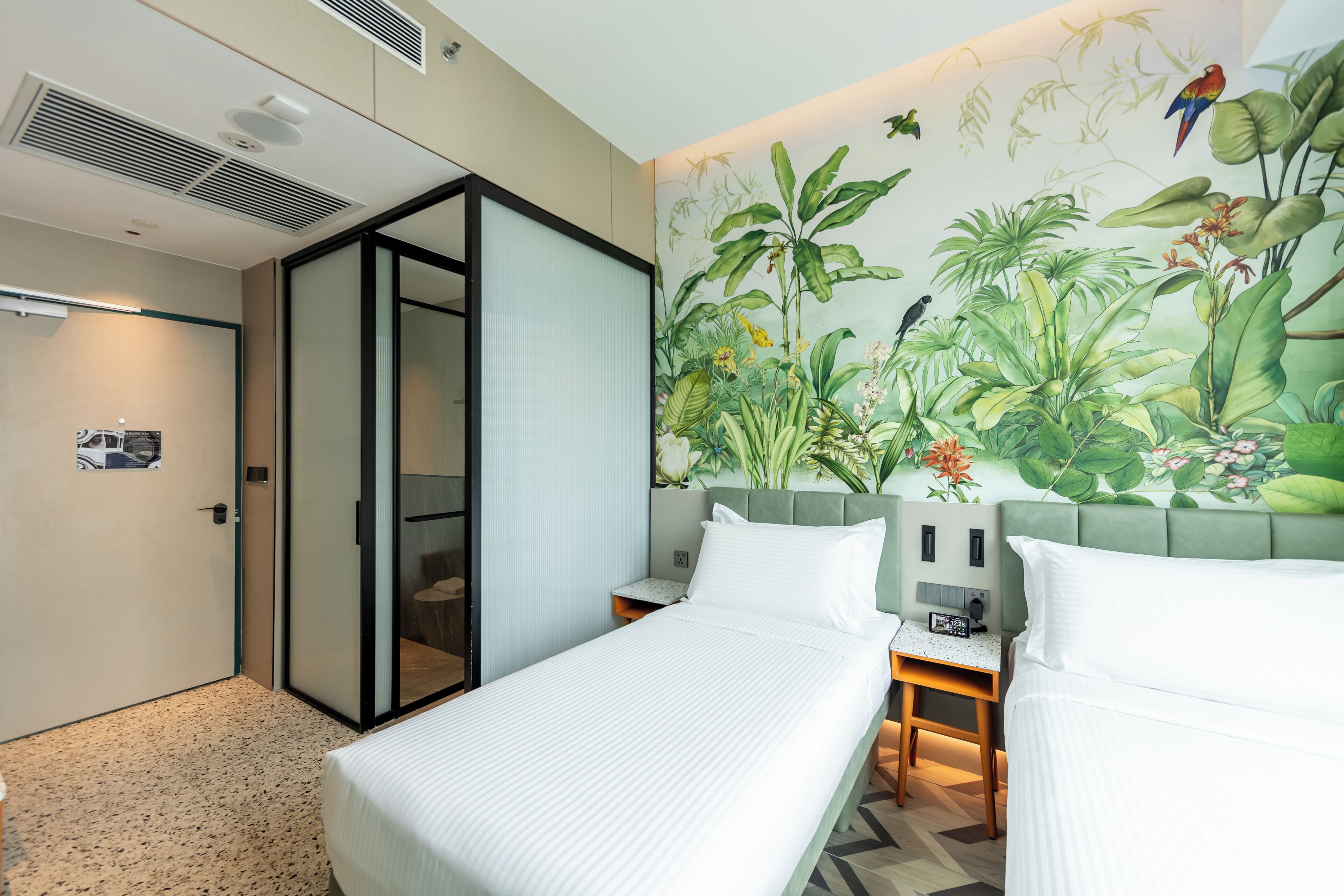Quarto de hotel com cama, pequena escrivaninha, telefone e porta deslizante.