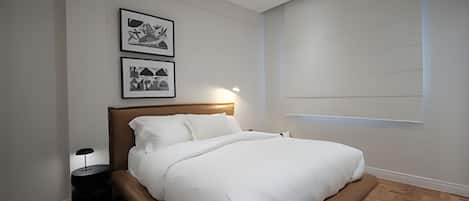 Um quarto moderno com uma cama de madeira, uma mesa de cabeceira e duas obras de arte abstrata emolduradas na parede.