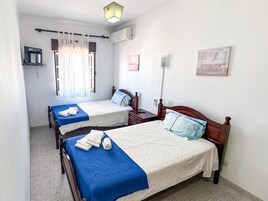 Quarto de hotel com duas camas de solteiro, televisão, ar condicionado e janela com cortinas.