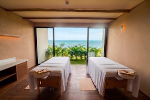 Um quarto com duas mesas de massagem, uma TV e vista para o oceano.