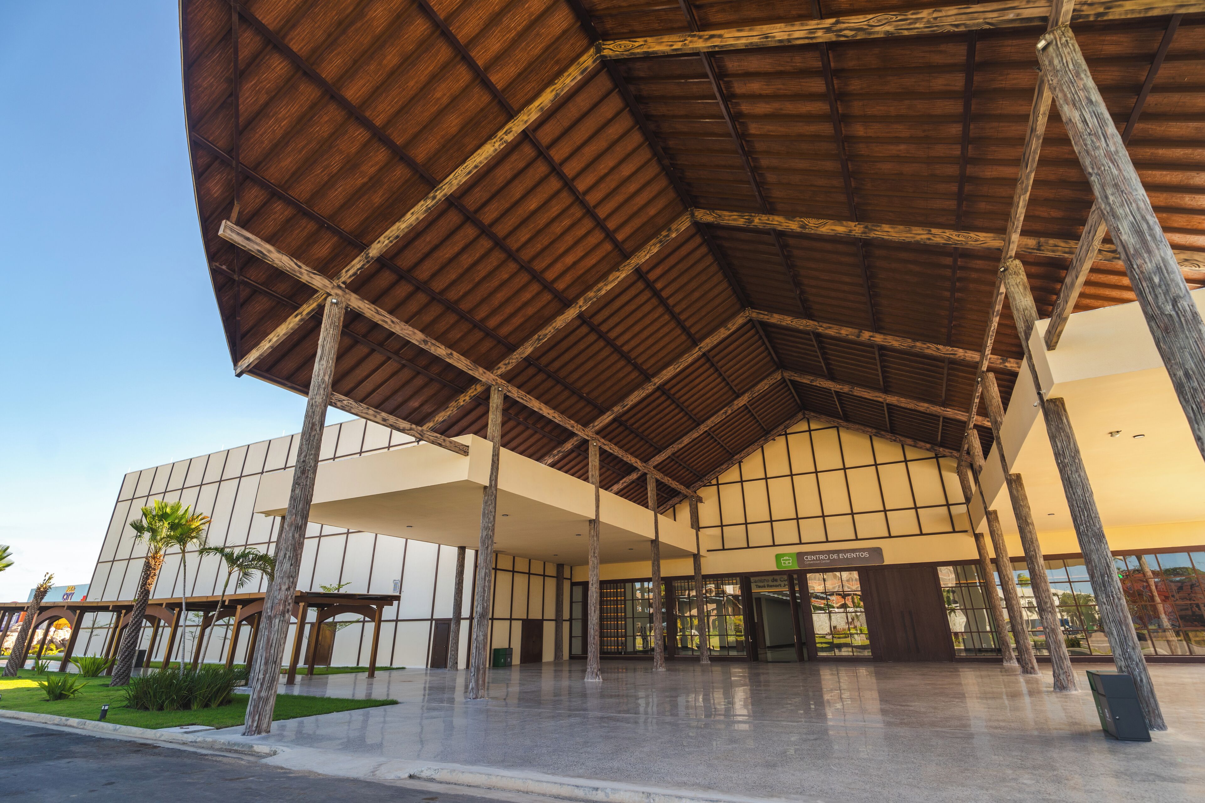 Um edifício com uma grande entrada coberta, fachada de vidro e uma placa indicando um centro de eventos.