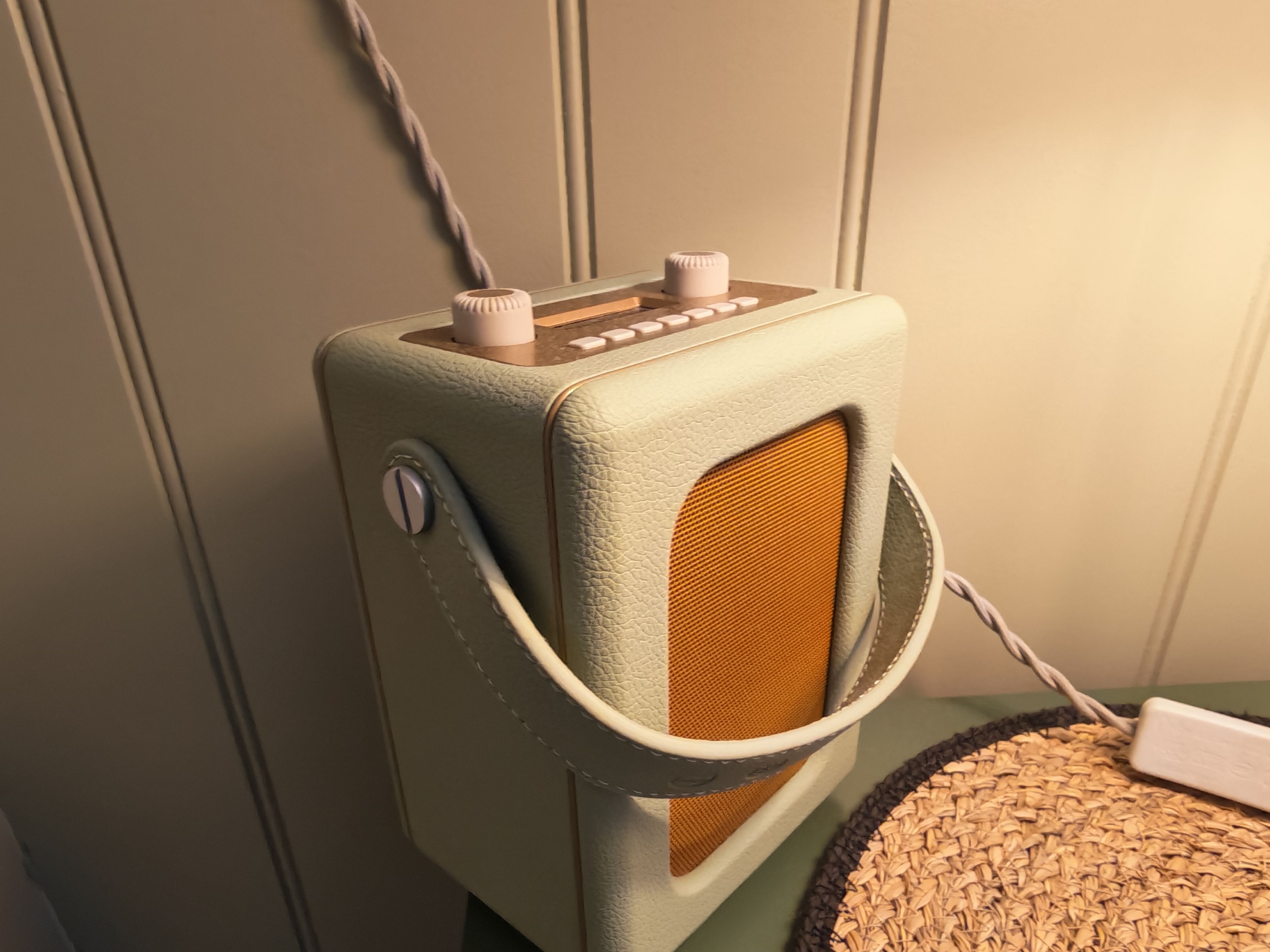 Rádio antigo com textura semelhante a couro, grade de alto-falante e cabo de alimentação.
