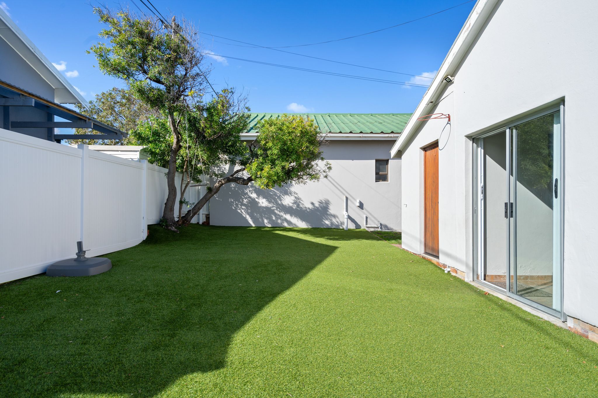 Uma casa moderna com fachada branca, telhado verde e gramado bem cuidado.