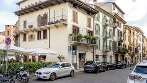 Uma rua com carros estacionados e um edifício com sacadas e persianas.