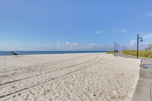 Uma praia arenosa com céu claro e mar calmo.