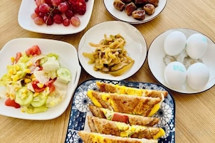 Uma mesa com vários pratos, incluindo uma salada, ovos fritos e um prato de carne.