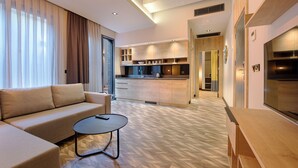 Uma sala de estar moderna com sofá, mesa de centro e área de cozinha com armários de madeira e bancada.