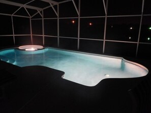 Piscina com borda curva, rodeada por área coberta com estrutura em grade.