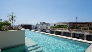 Piscina no terraço com águas azul-claras, cercada por edifícios modernos e áreas de estar ao ar livre.