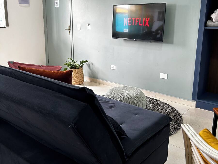 Uma sala de estar moderna com uma grande TV de tela plana na parede exibindo 'NETFLIX'.