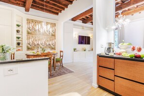 Uma cozinha moderna com armários de madeira, uma área de refeições com mesa e cadeiras, e uma parede decorativa com padrão floral.