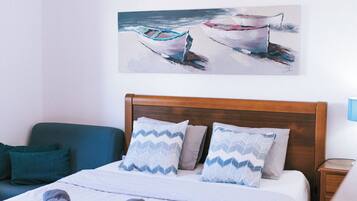 Uma cama bem arrumada com cabeceira de madeira, um abajur azul pendurado e um quadro com barcos na parede.