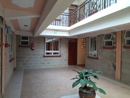 Interior espaçoso com teto alto, área central aberta e varanda com grade de ferro forjado.