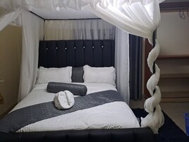 Uma cama com dossel, cabeceira e almofadas.