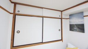 Quarto com porta deslizante de madeira, parede branca e pintura de uma estrada a convergir para o horizonte.