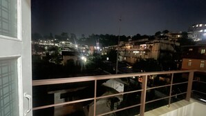 Uma varanda com vista para um horizonte urbano noturno, com edifícios e postes de luz.