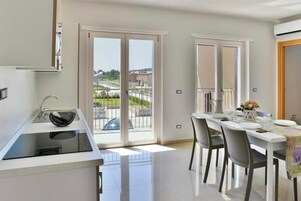 Apartamento, varanda | Cozinha privada | Uma cadeira de bebé, mesas de jantar 