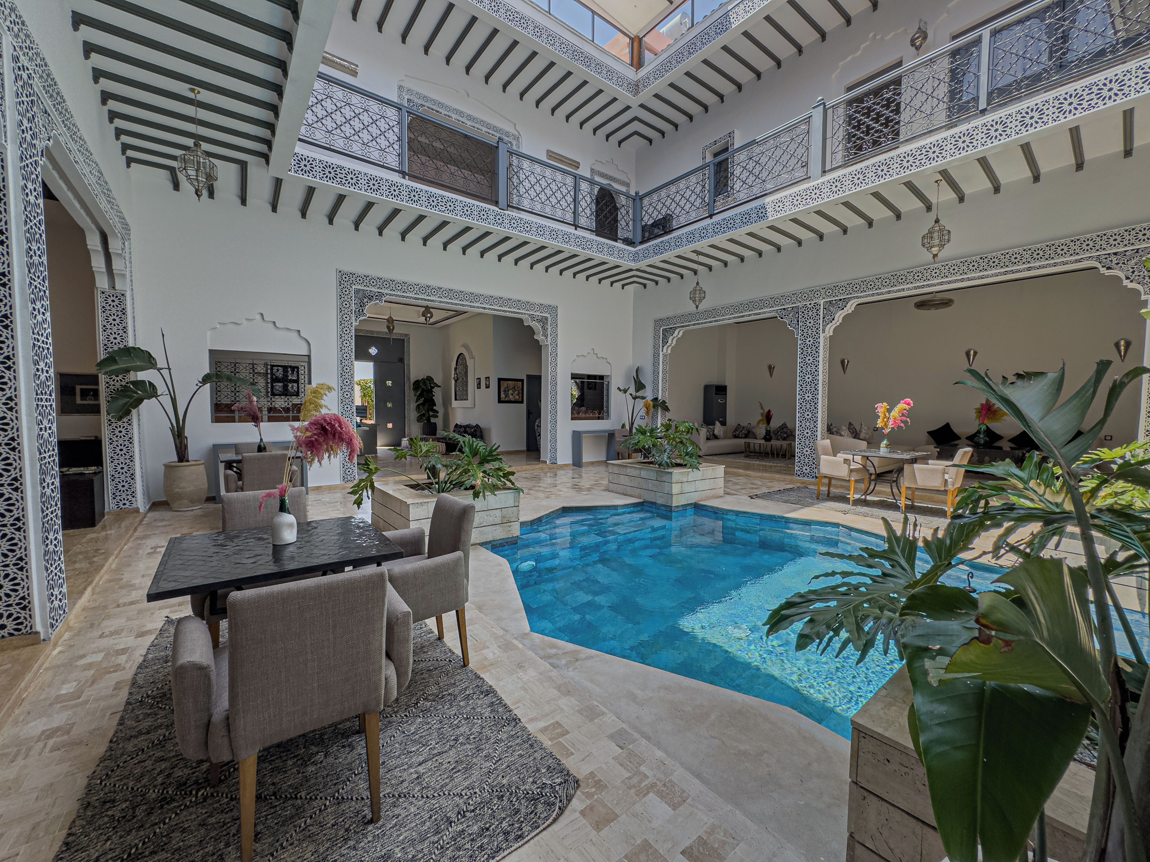 Uma área de piscina interna ampla, com teto alto e elaborada estrutura de treliça branca.