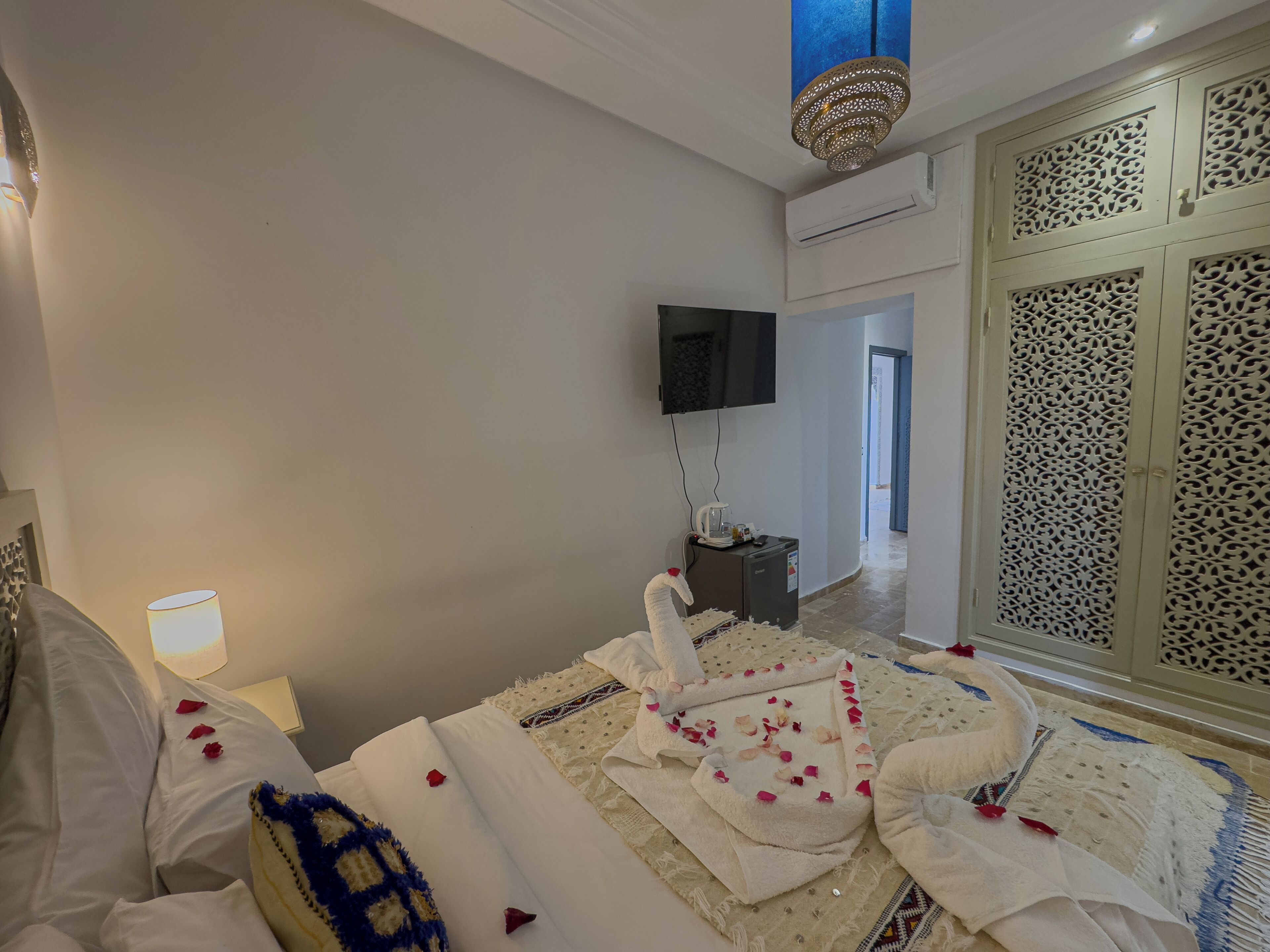 Quarto de hotel com uma cama, televisão, painel decorativo e ar condicionado.
