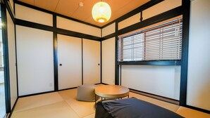 Um quarto japonês tradicional com tatames, uma mesa baixa e uma janela com persianas.