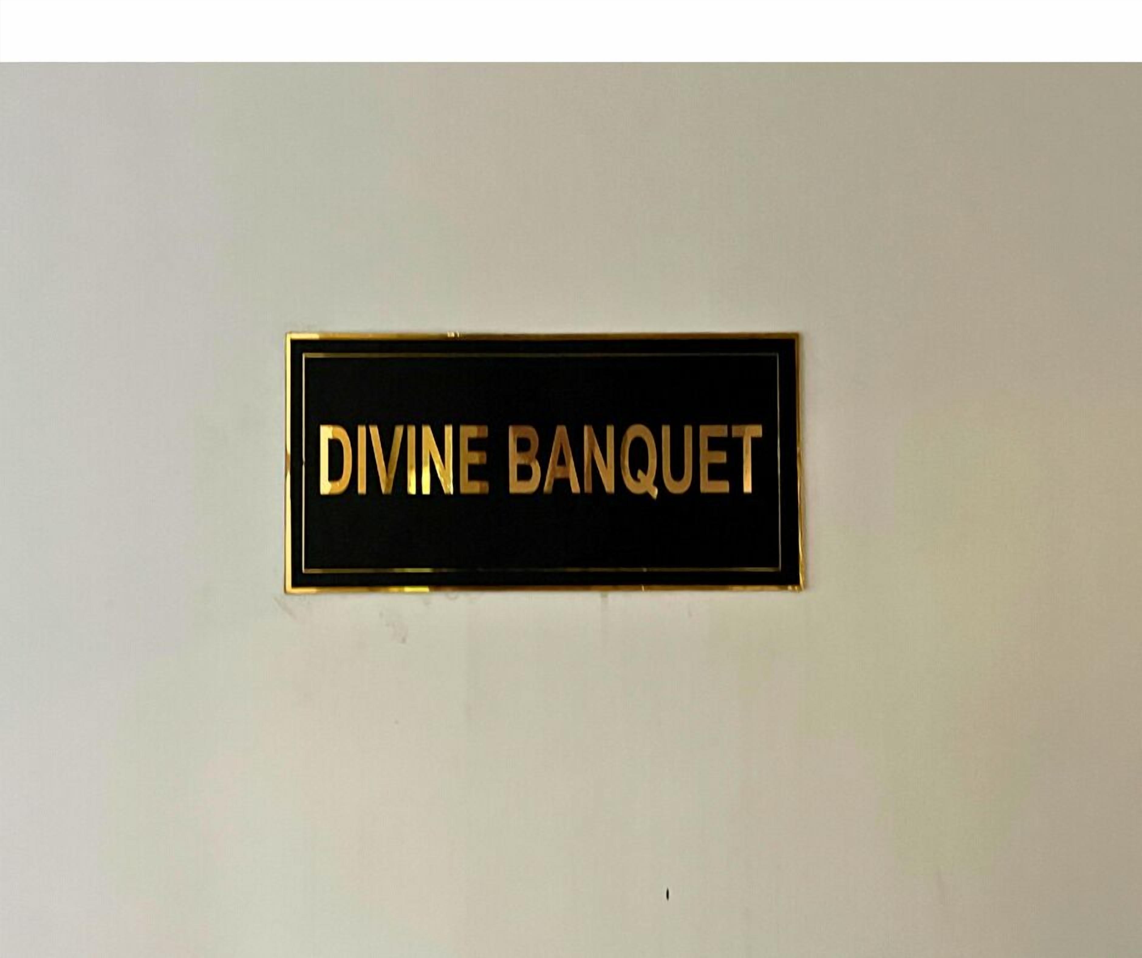 Um letreiro com o texto 'DIVINE BANQUET' em uma parede branca.