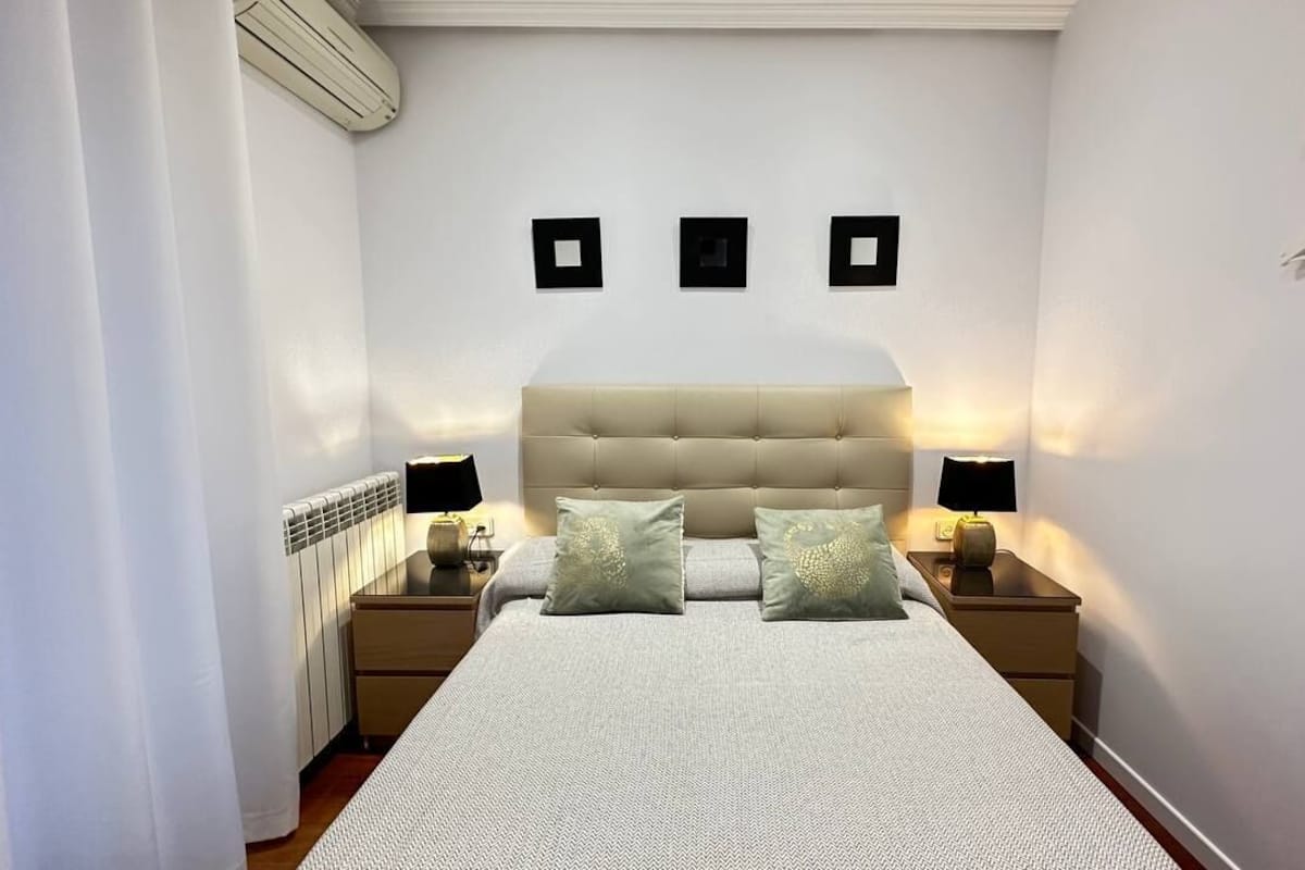 Quarto com uma cama grande, duas mesas de cabeceira e um ar condicionado fixado na parede.