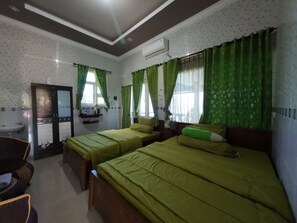 Quarto de hotel com duas camas, pia, espelho e janela com cortinas verdes.