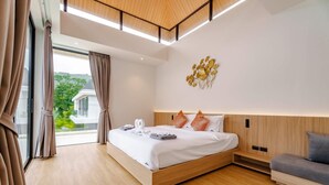 Quarto moderno com cama grande, um sofá e vista para o verde lá fora.