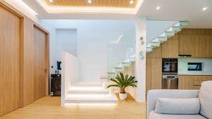 Uma sala de estar moderna com um sofá, uma mesa de centro e uma escada que dá para uma área de cozinha.