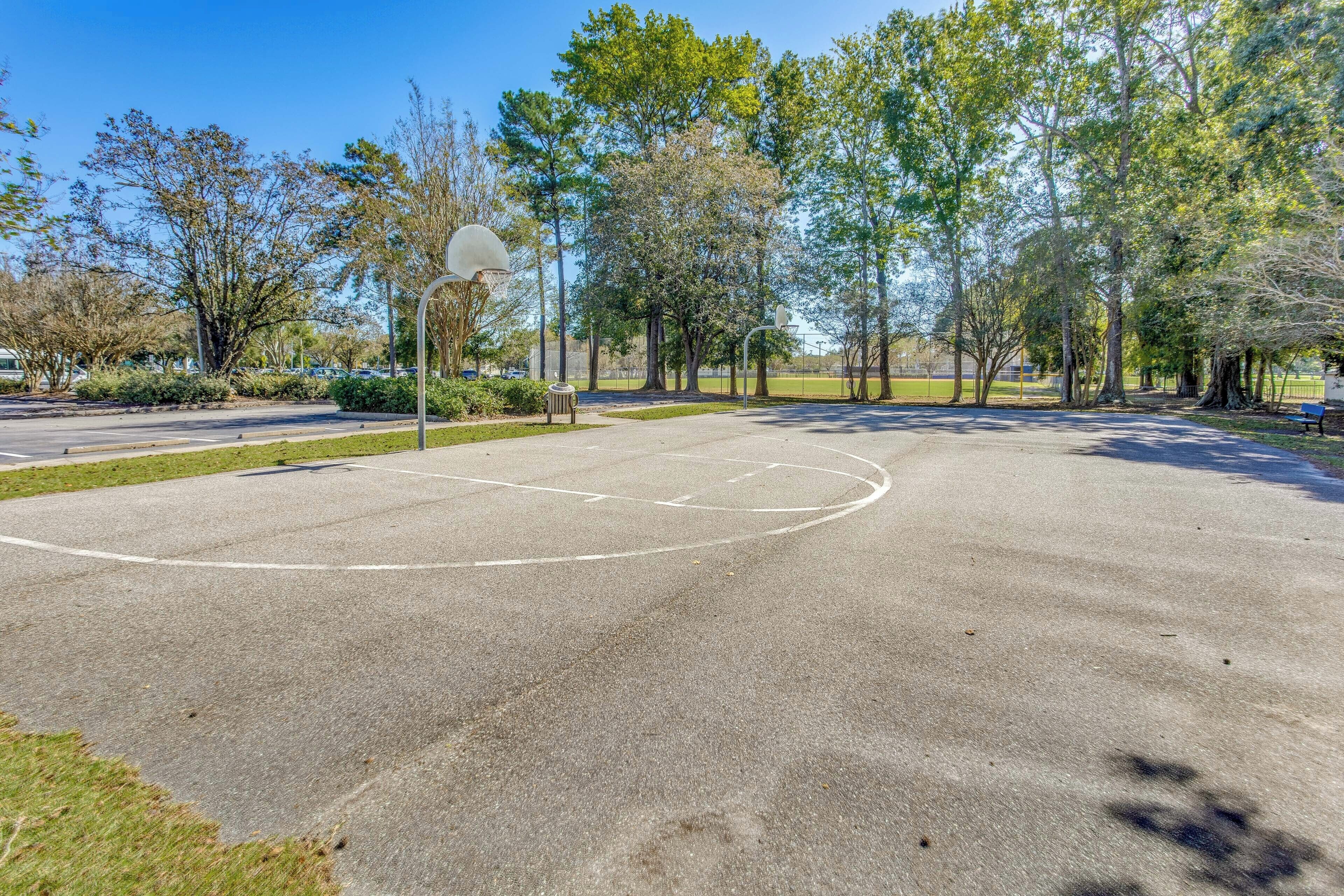 Quadra de basquete ao ar livre com árvores e céu limpo.