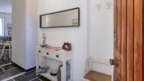 Um corredor com um aparador branco, um espelho e uma porta de madeira.
